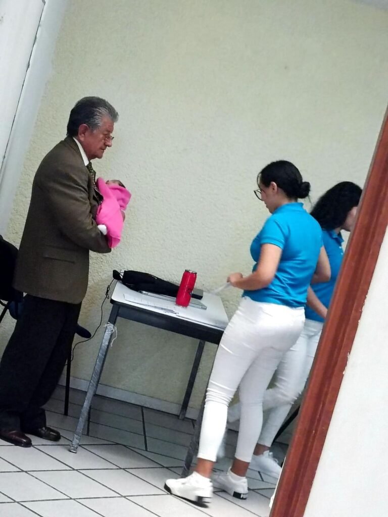 Docente de la UMSNH carga al bebé de una alumna durante su clase